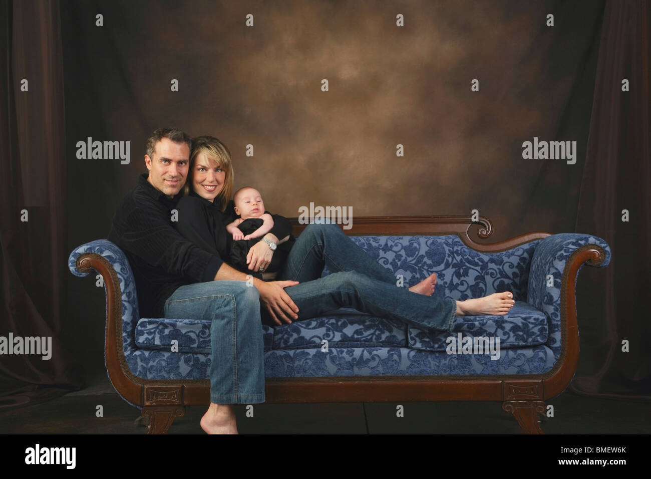 Portrait d'un couple avec un bébé sur un canapé Photo Stock - Alamy