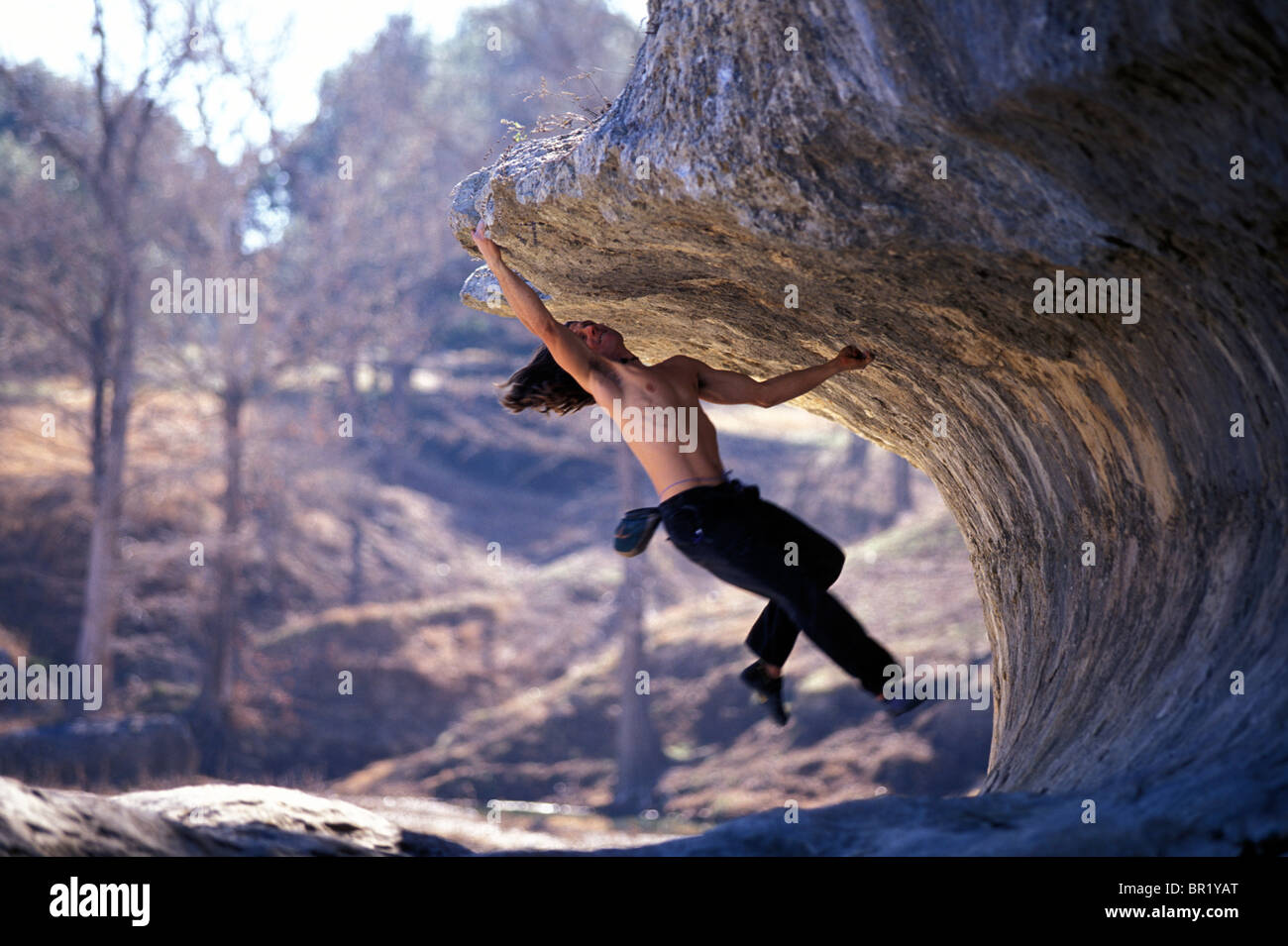 Un grimpeur torse nu bouldering sur un surplomb dans les bois près de ...