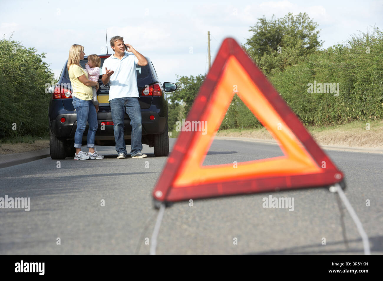 Famille décomposée sur route de campagne avec des signes de détresse en ...