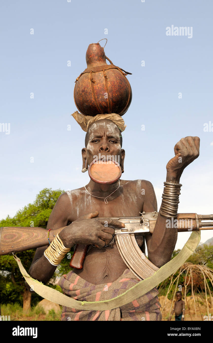 Femme de la tribu Mursi avec une carabine et une plaque dans sa lèvre ...
