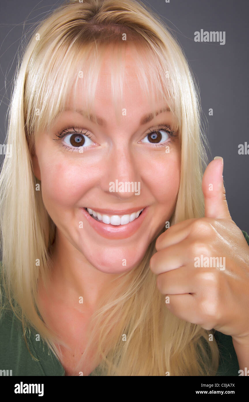 Femme blonde drôle avec le pouce sur un arrière-plan gris Photo Stock ...