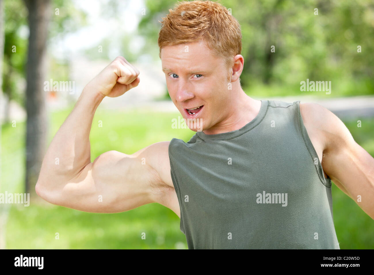 Jeune homme musclé montrant ses biceps contre l'arrière-plan flou Photo ...