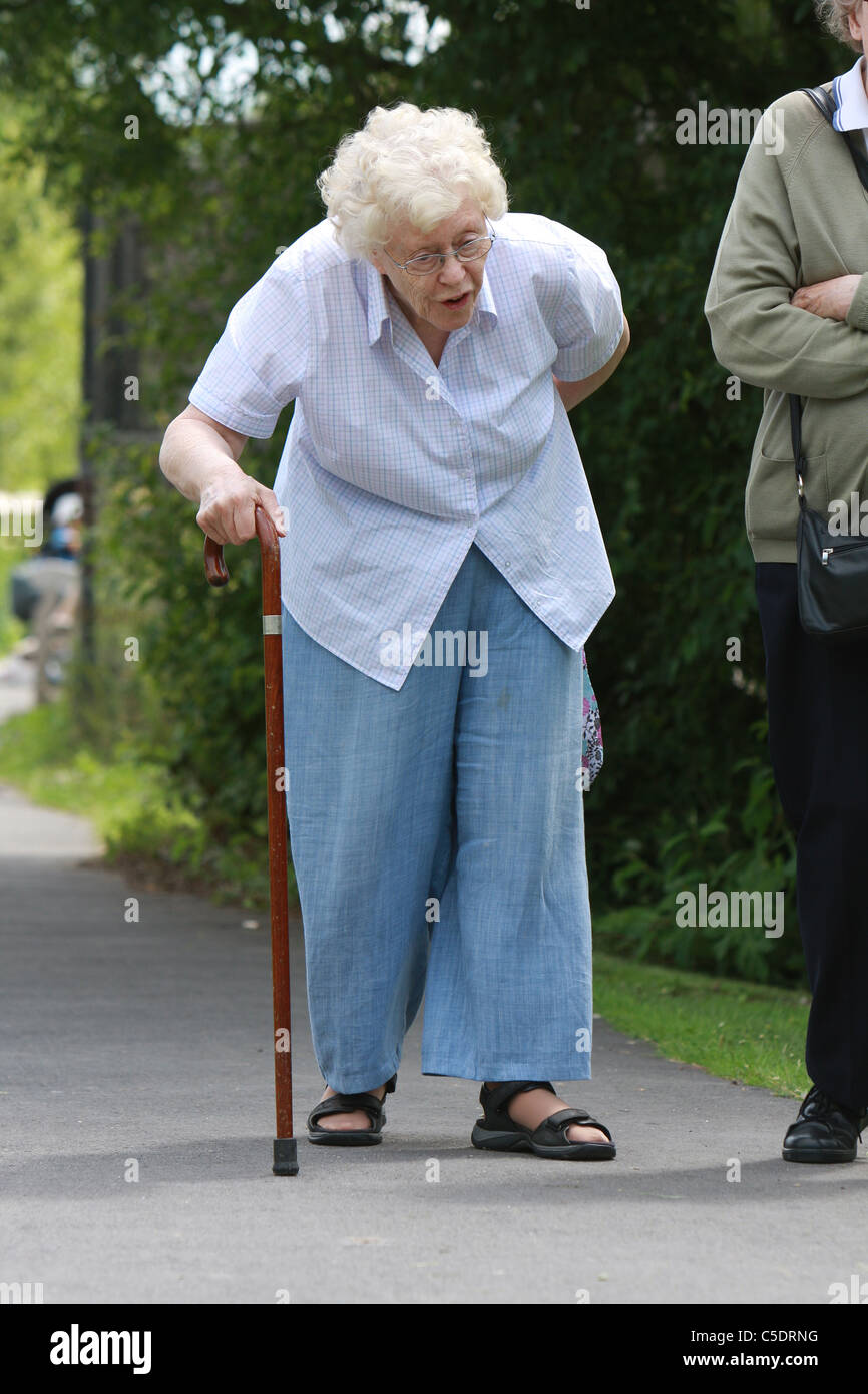 Une vieille dame marche avec l'aide d'un bâton de marche Photo Stock ...