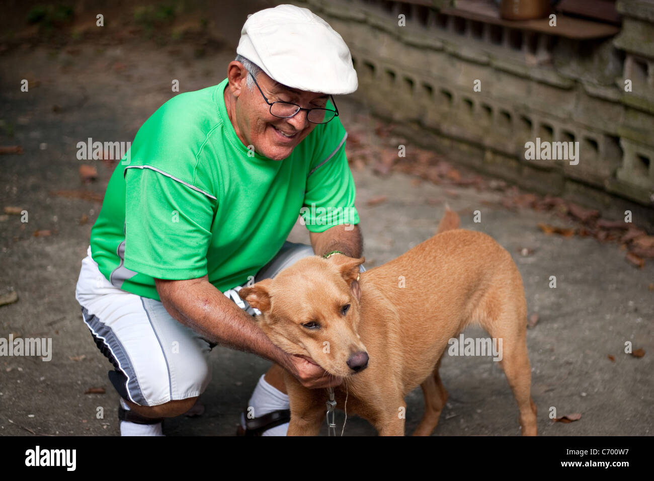 Un vieil homme hispanique Senior citizen de flatter son chien avec un ...