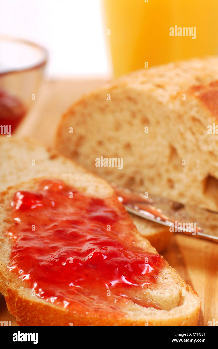 Du pain avec de la confiture de fraise répartis sur elle avec un verre ...