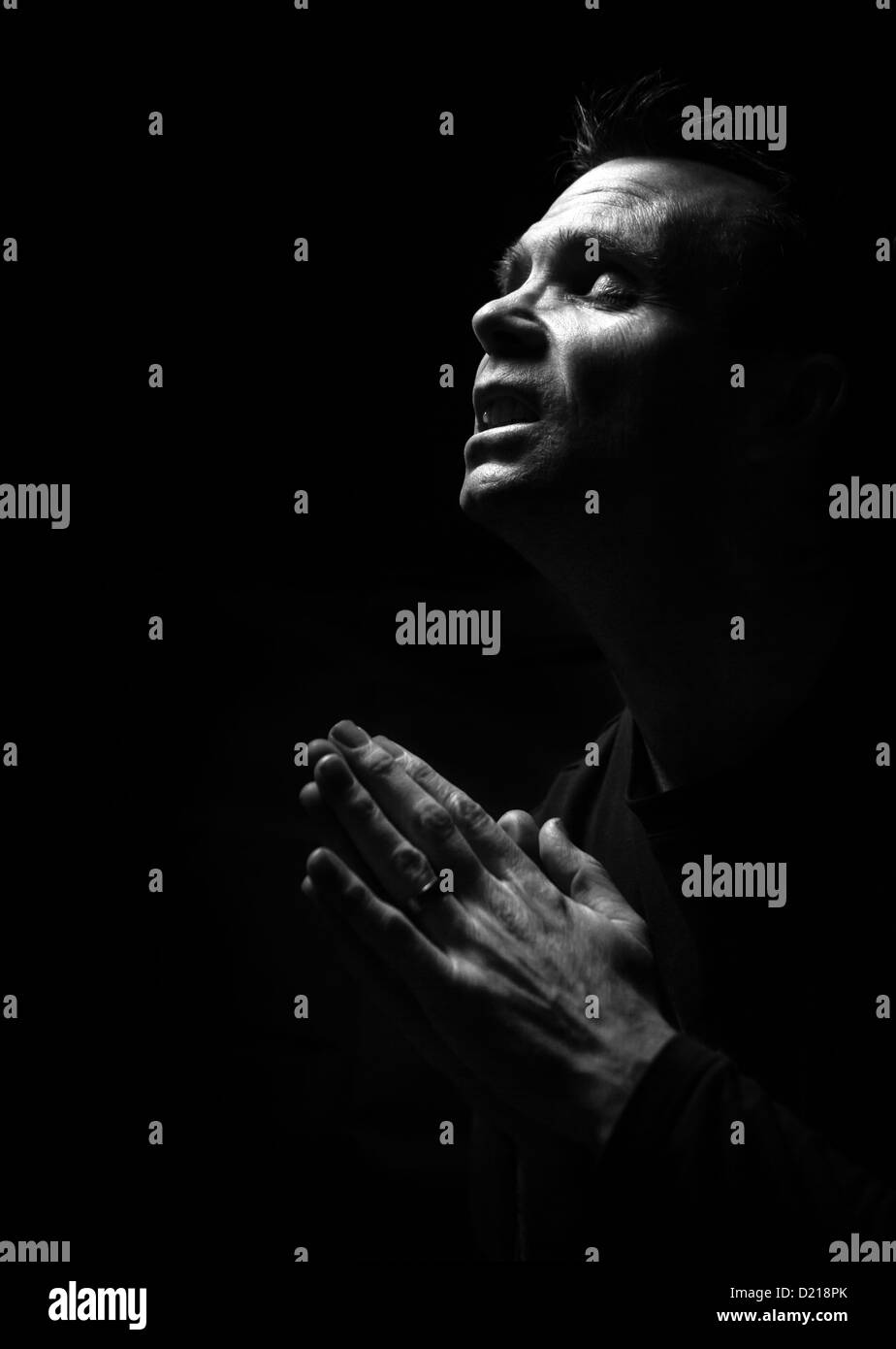Une image en noir et blanc d'un homme à genoux à prier Dieu Photo Stock ...