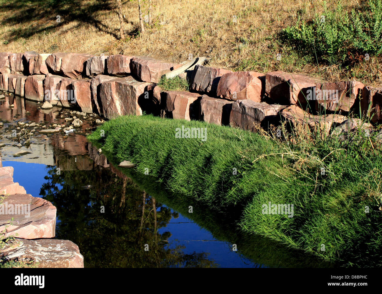 Une photo montrant un ruisseau traversant un paysage avec un mur de ...