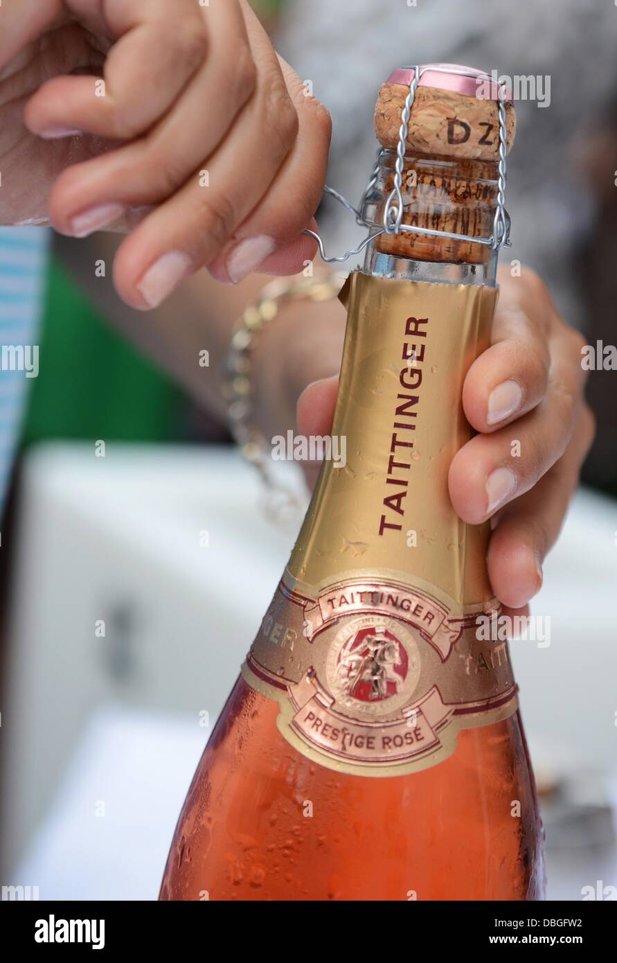 Une femme ouvre une bouteille de champagne Taittinger et ressemble à un ...