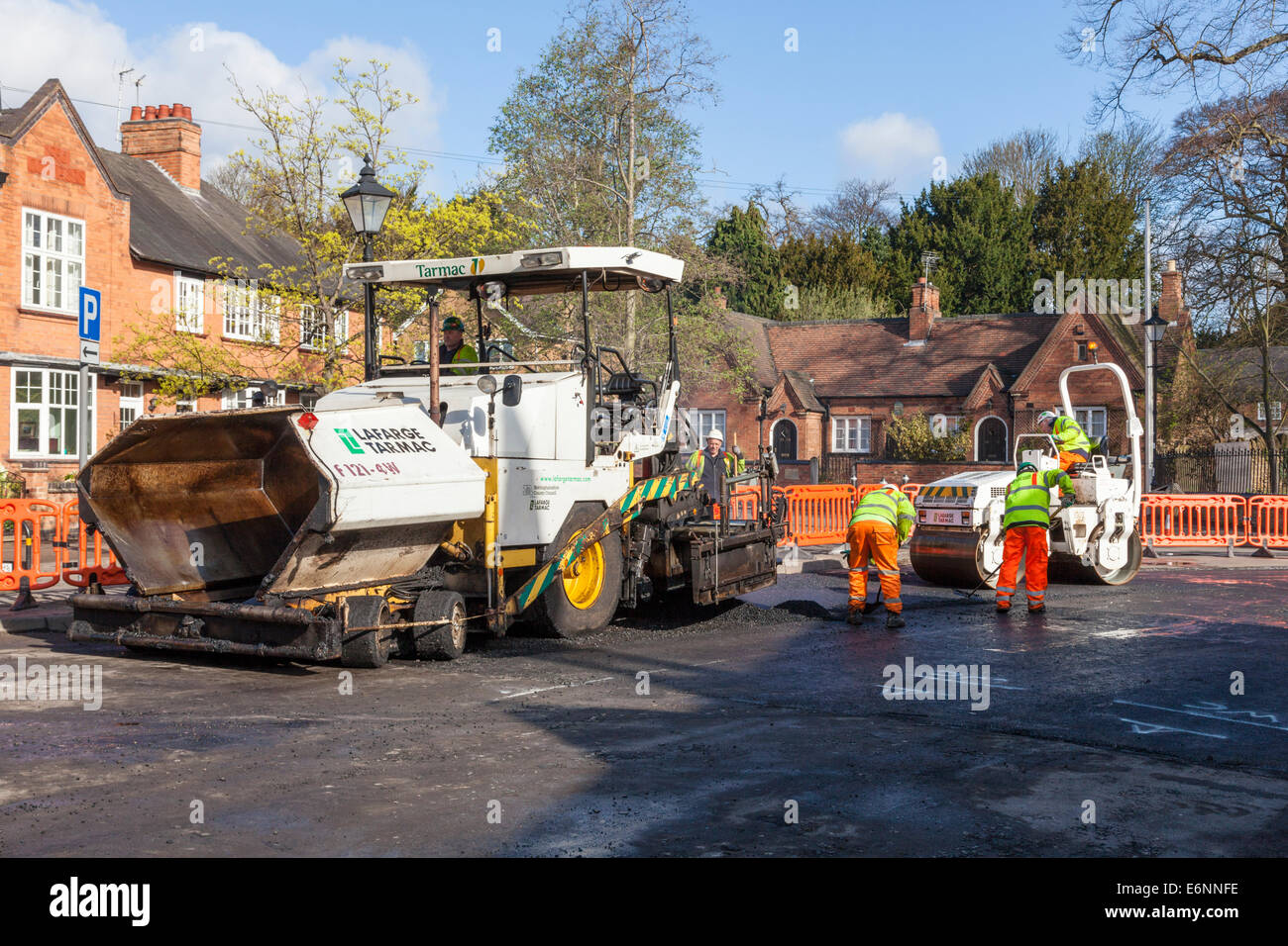 Les travaux routiers. Paver, road roller road et les travailleurs lors ...