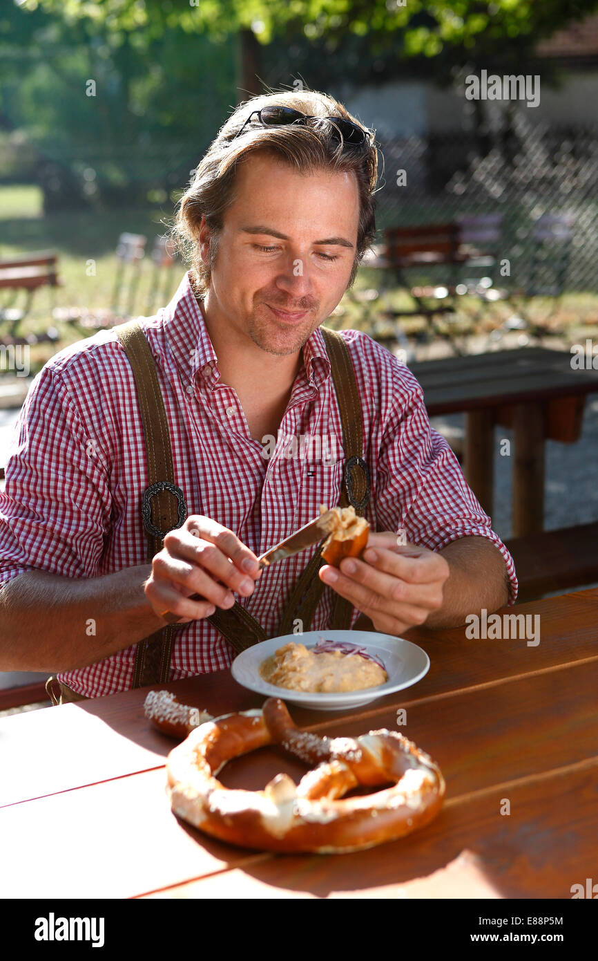 Attractive caucasian man mange du fromage traditionnel avec bretzel ...