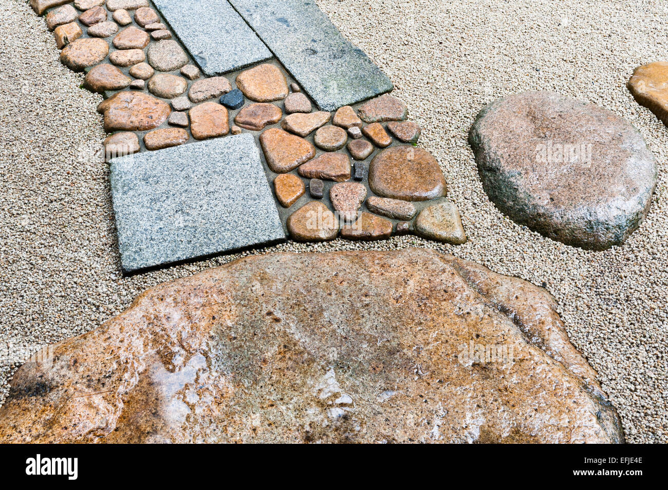 Un chemin dans un jardin japonais fait de pavés et de blocs de granit ...
