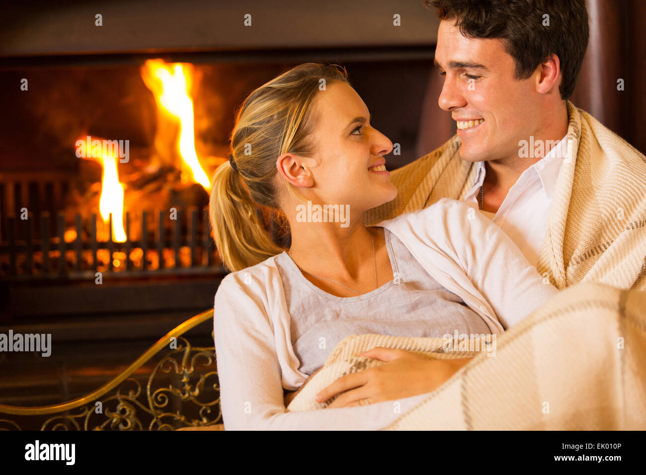 Happy young couple sitting on couch devant le foyer à la maison Photo ...