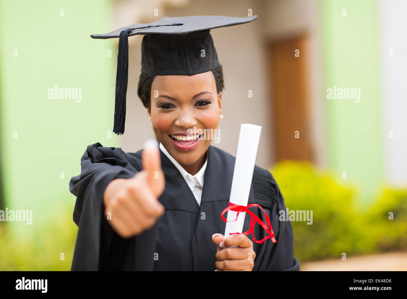 Belle femme africaine graduate giving thumb up à la cérémonie de remise ...
