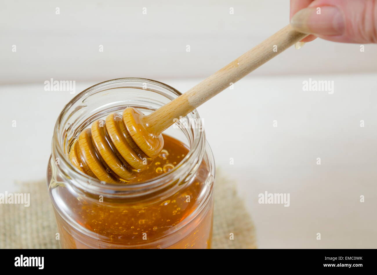 Des gouttes de miel dans un bocal en verre d'une cuillère en bois Photo ...