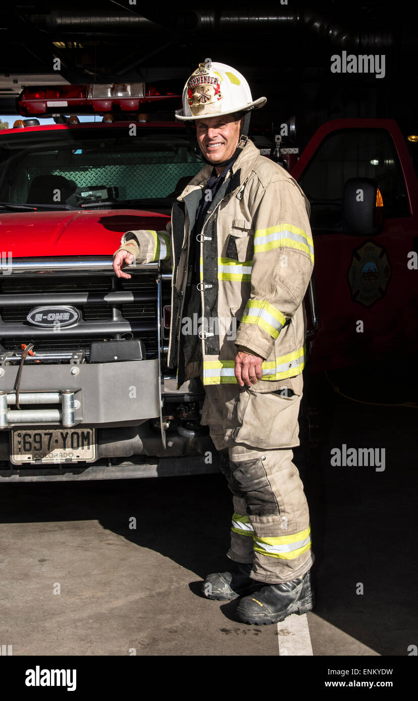 Le commandant des pompiers en tenue de feu à côté de chariot de ...