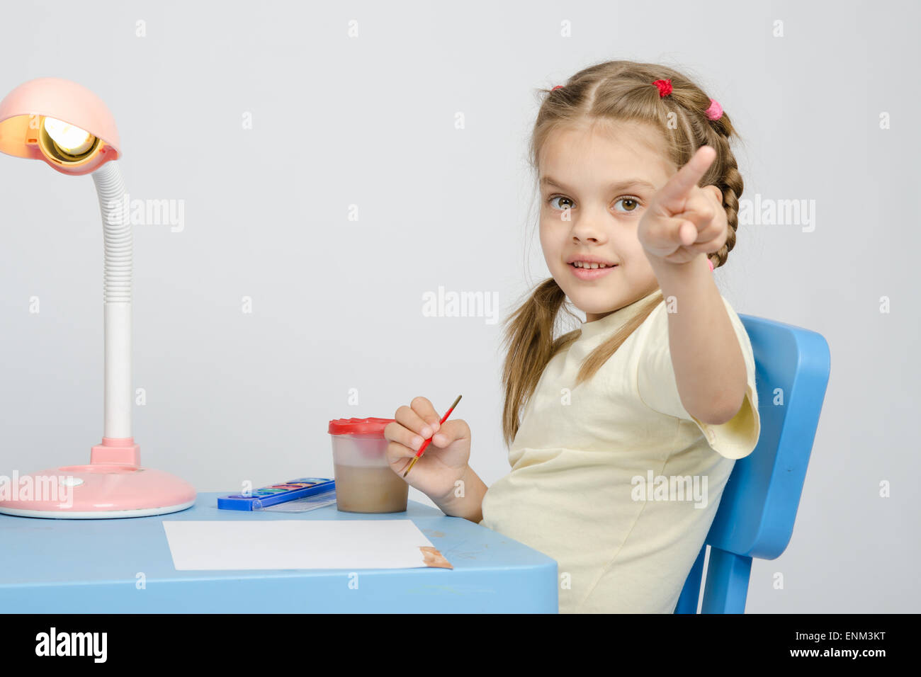 Fillette de six ans Les Européens s'appuie sur une feuille de papier peint assis à la table ...