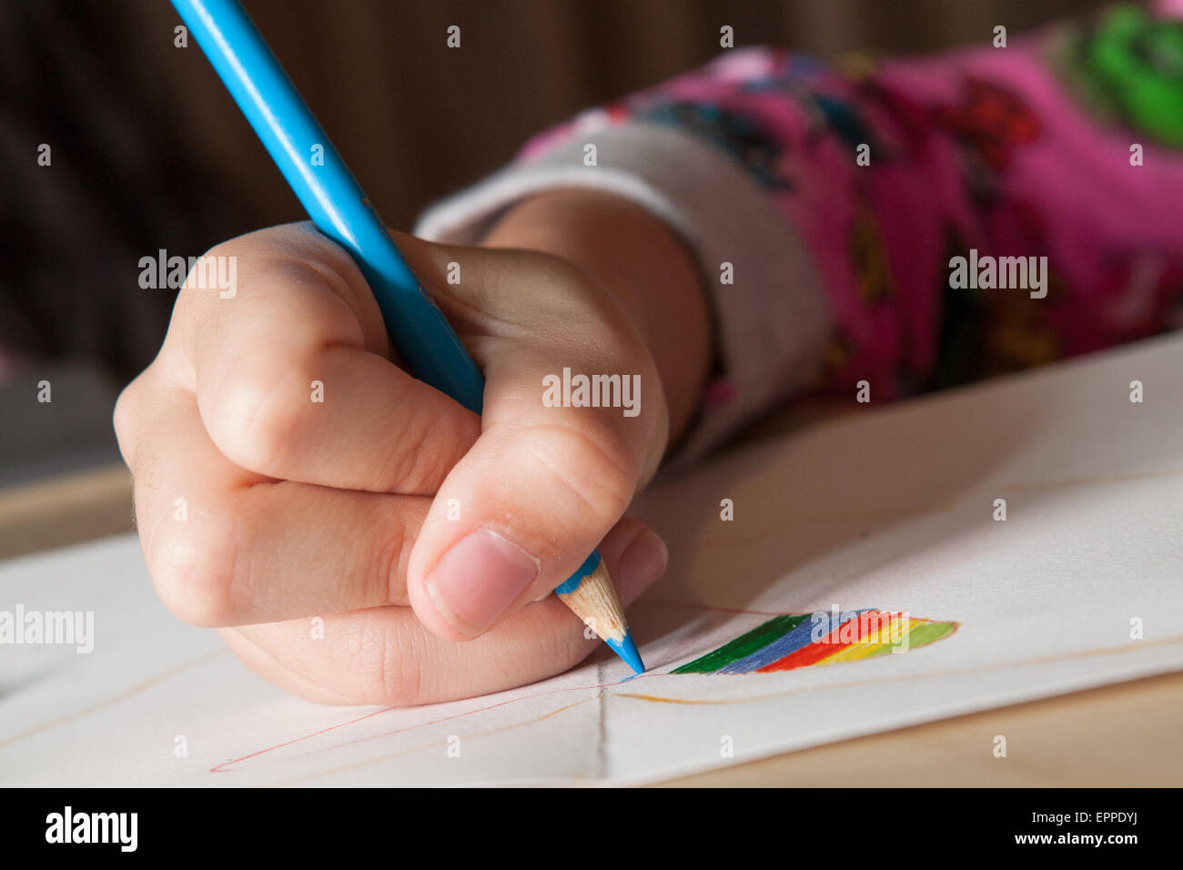 La main de l'enfant avec dessin au crayon bleu sur feuille blanche ...