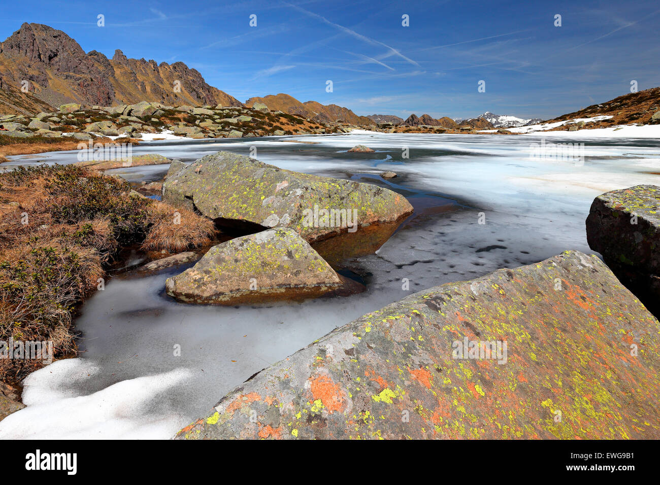 Lac alpin en dégel. Lac d'Ezze. Roches porphyriques avec lichens. Le ...