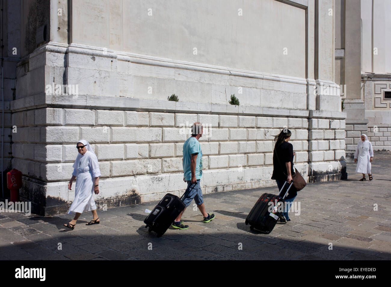 Deux religieuses passent devant les touristes avec des bagages dans la ...
