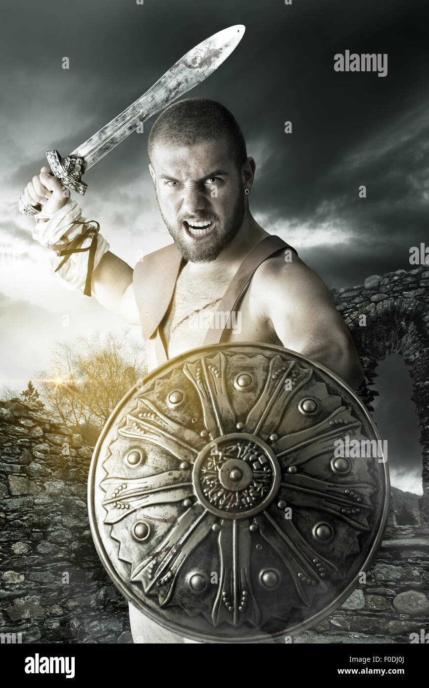 Gladiator ou guerrier posant avec le bouclier et l'épée en plein air ...