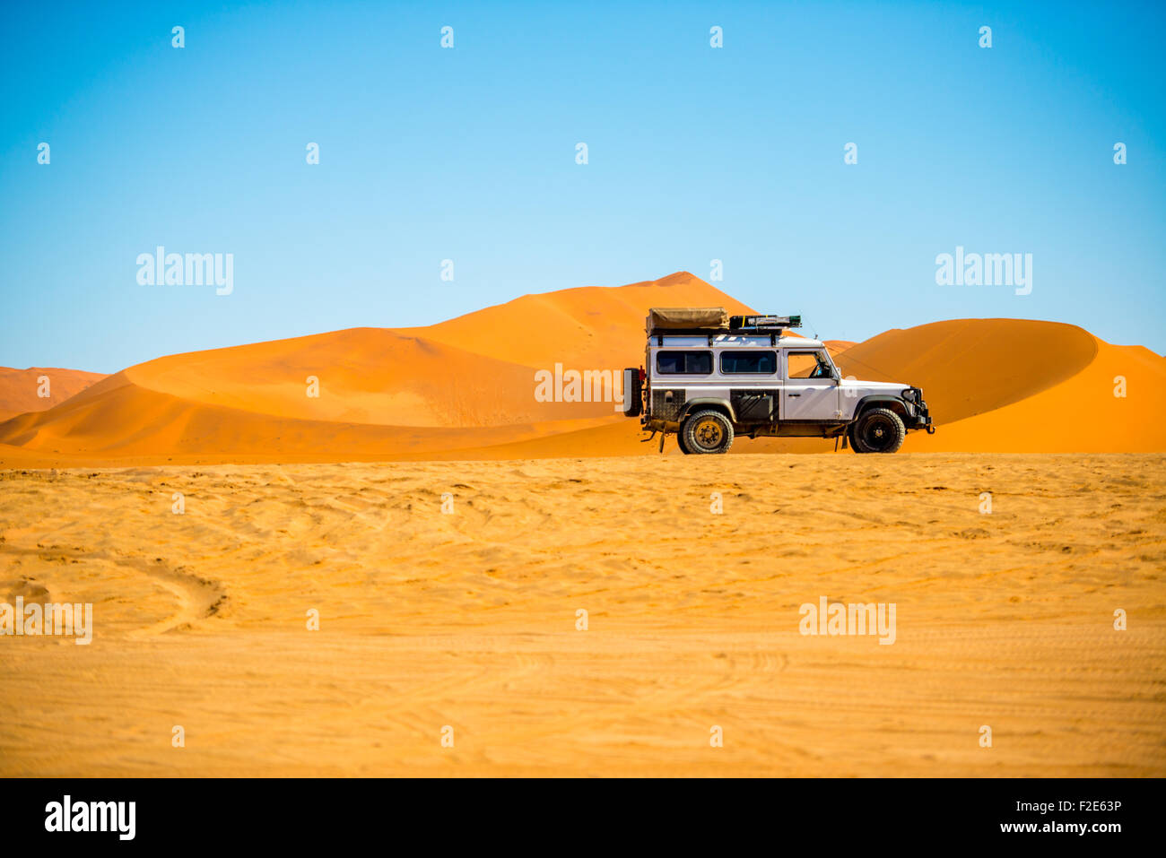 Land Rover Defender 110 stationnés dans le désert avec des dunes au ...