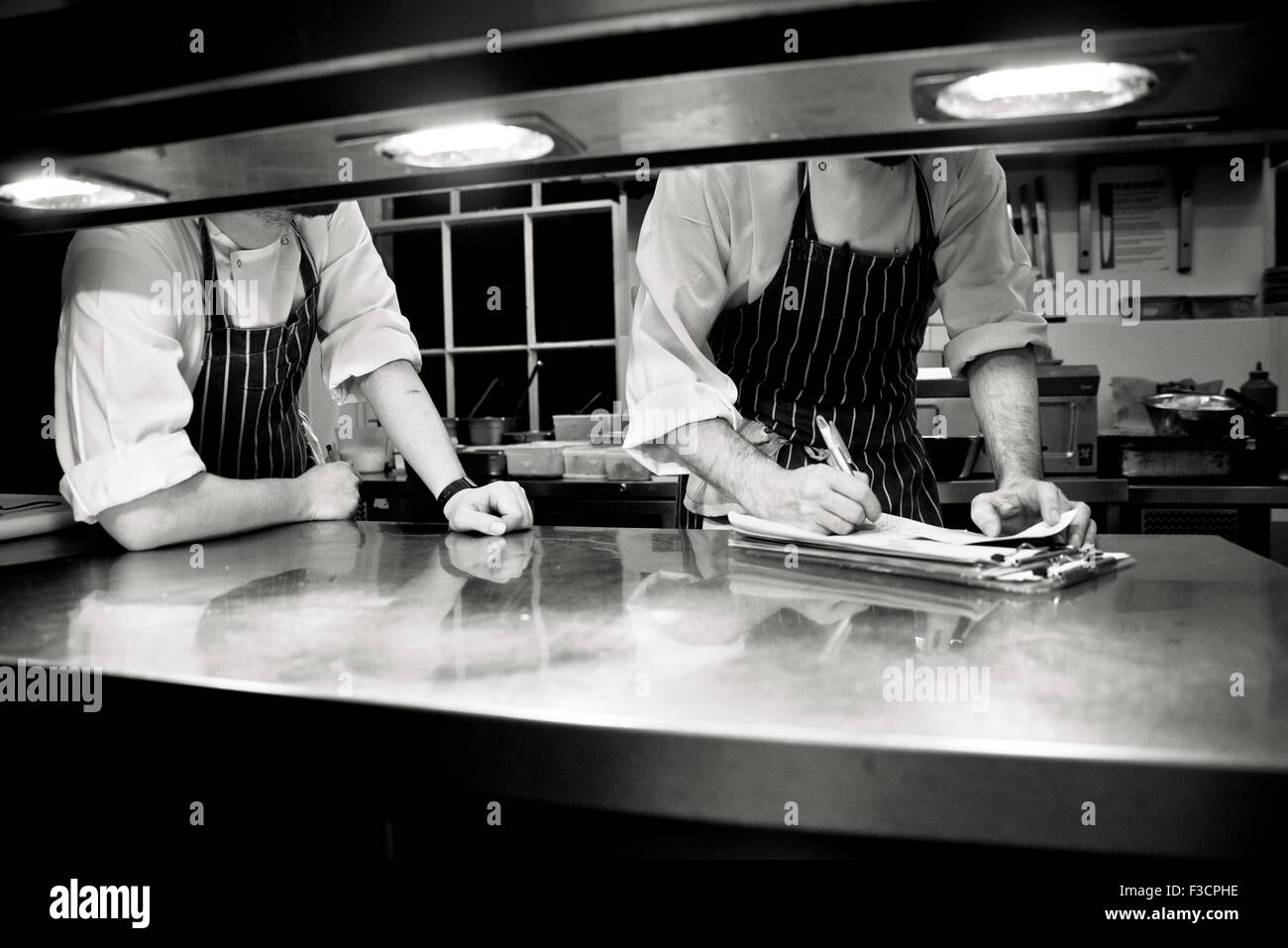 Chefs menu planning in restaurant kitchen Photo Stock - Alamy
