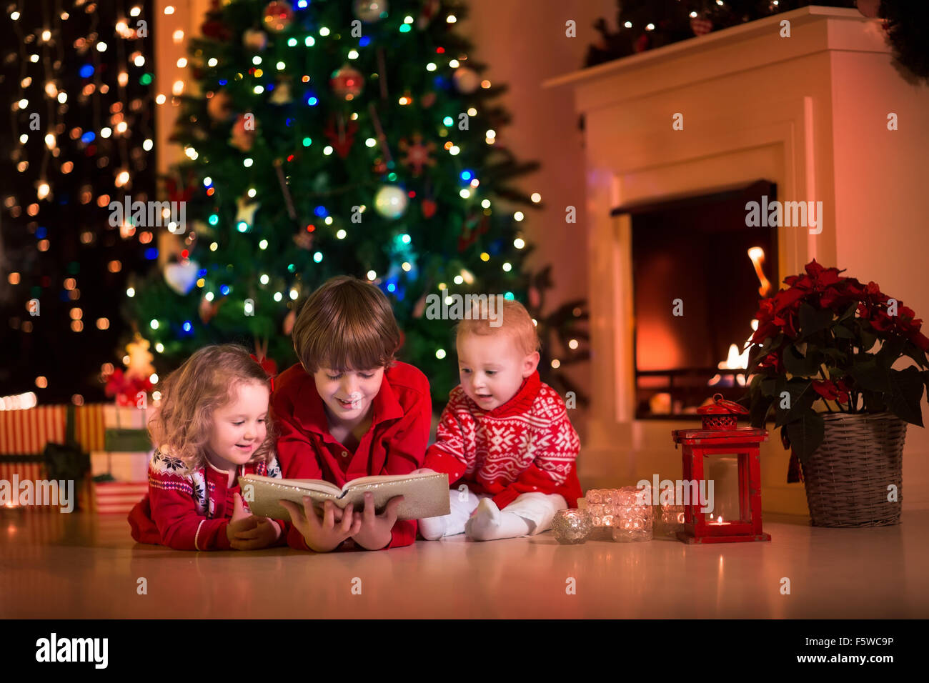Les enfants lisent un livre et ouvrir des cadeaux à cheminée la veille ...