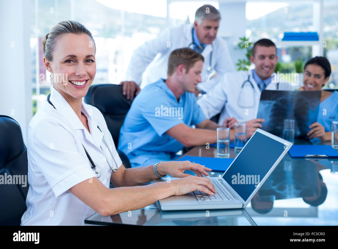 Beautiful smiling doctor de taper au clavier avec son équipe derrière ...