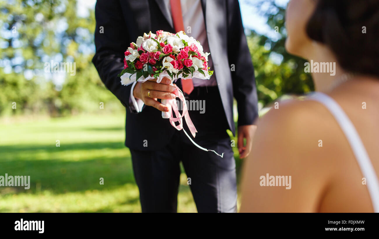 Le groom holding bouquet de mariage pour son épouse dans le jour du ...