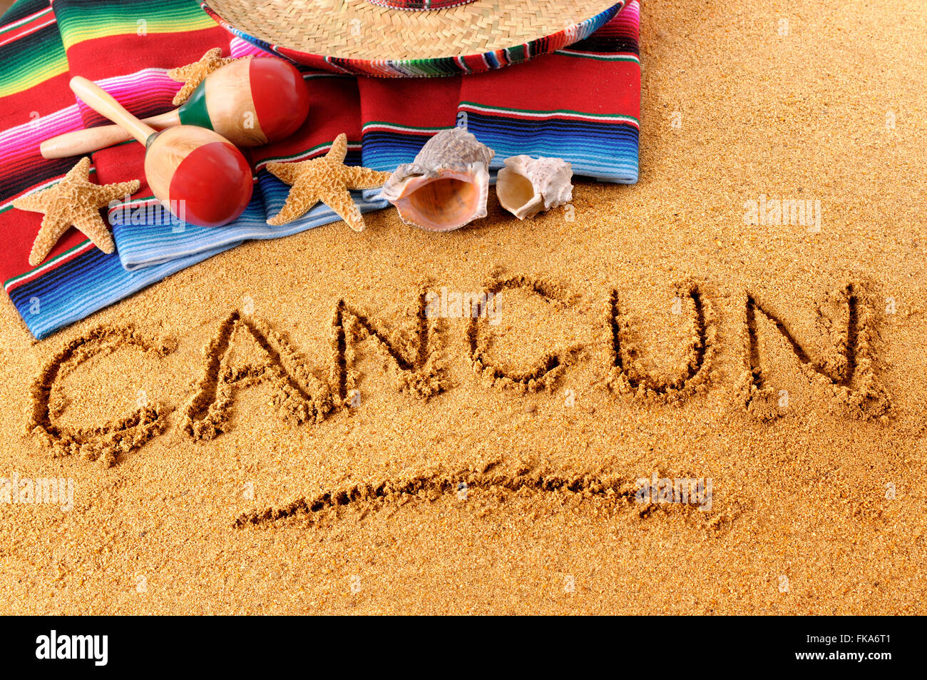 Le mot Cancun écrit dans le sable sur une plage mexicaine, avec chapeau ...
