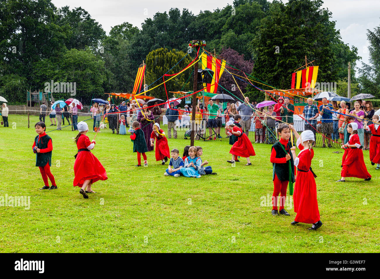 Les enfants en costume médiéval Maypole de danser dans la pluie pendant ...