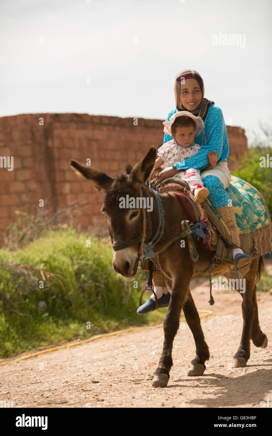 Une femme et son jeune enfant ride un âne vers le bas une route de ...