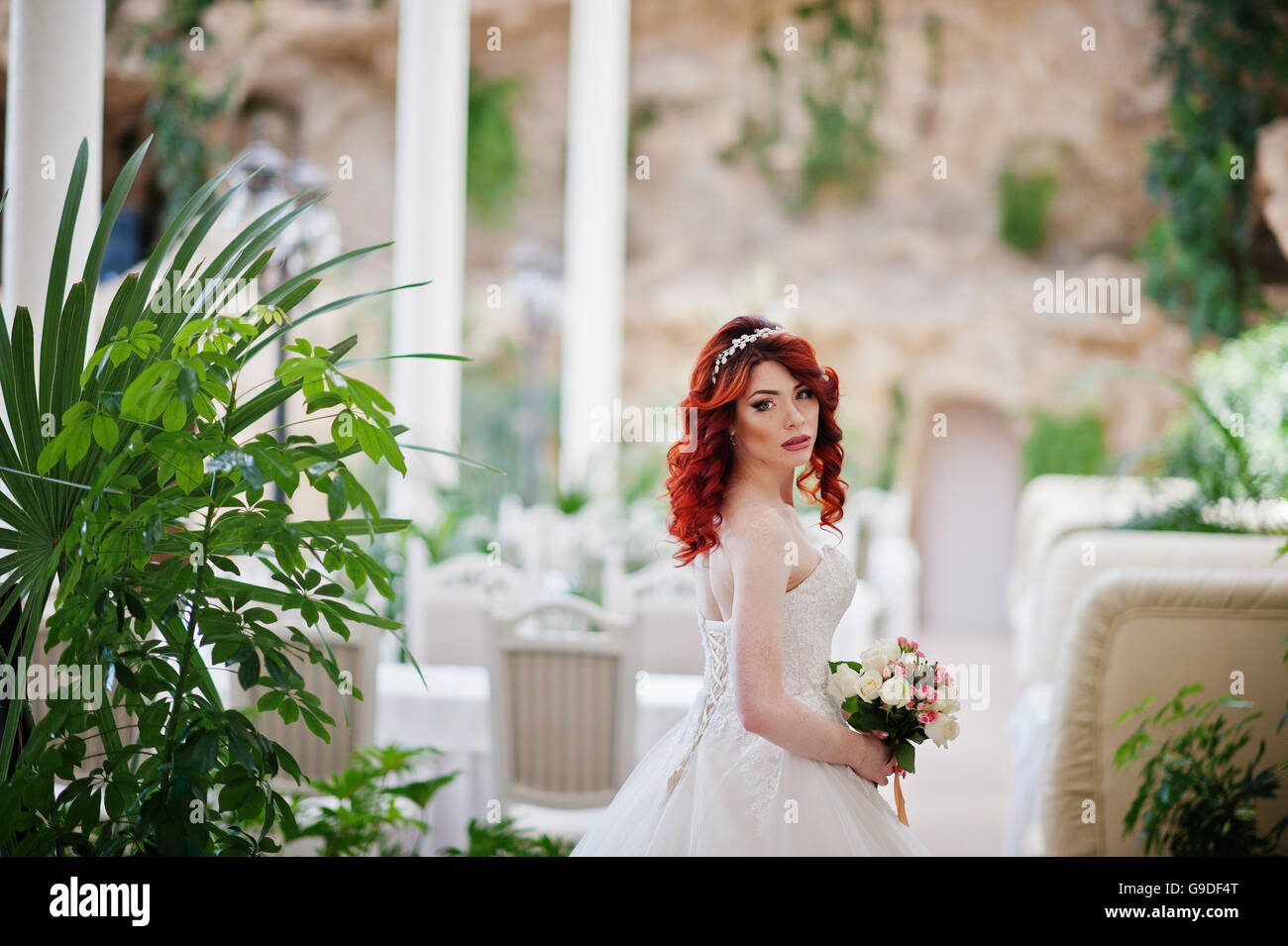 Rousse charmante épouse modèle avec bouquet de mariage à la main posée ...