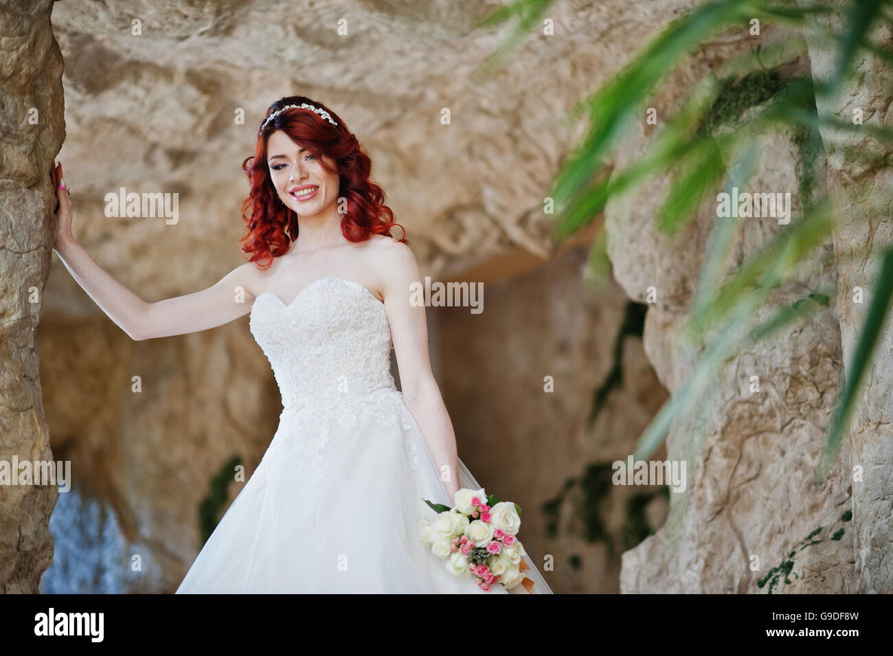 Rousse charmante épouse modèle avec bouquet de mariage à la main posée ...