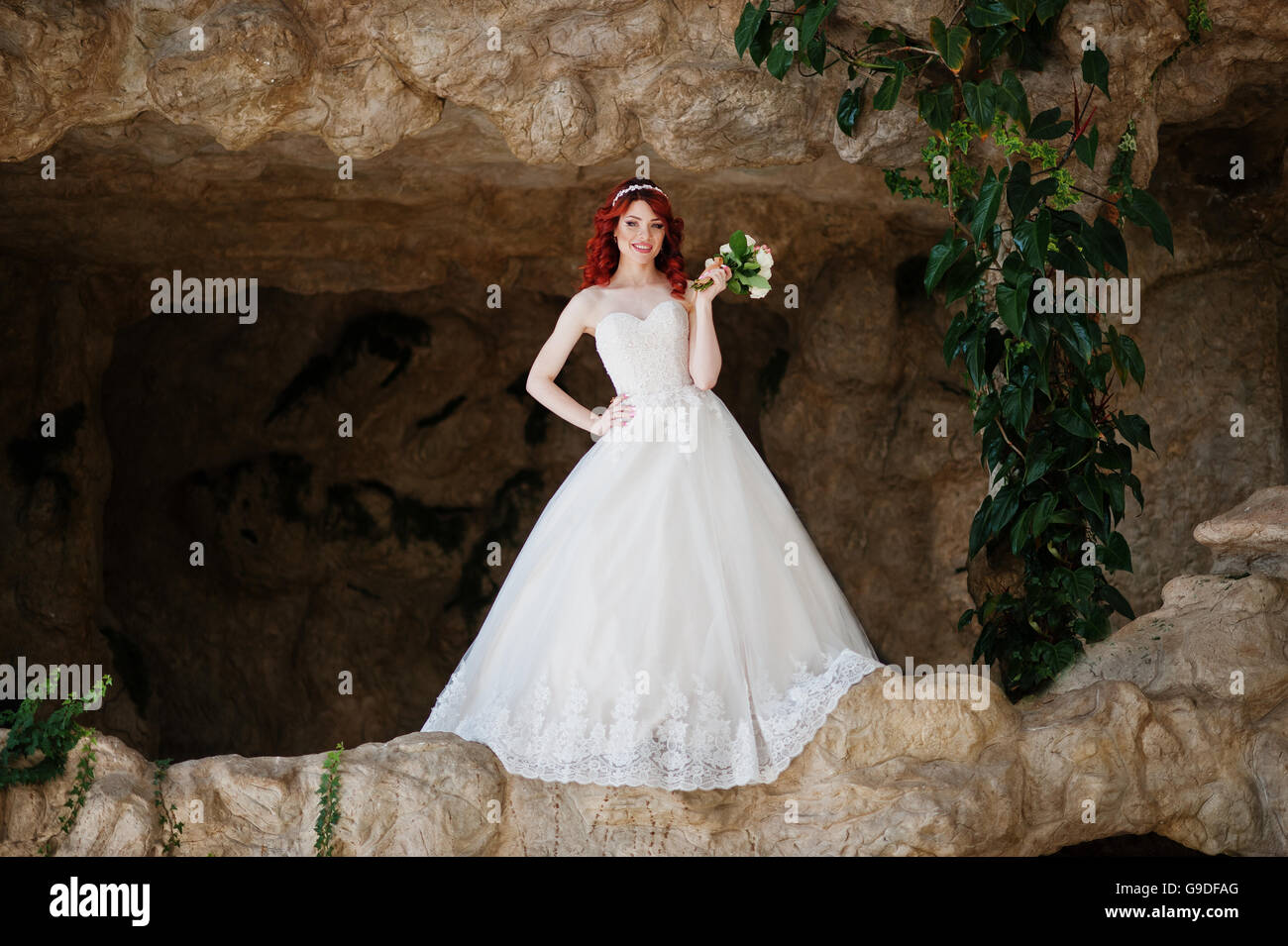 Rousse charmante épouse modèle avec bouquet de mariage à la main posée ...