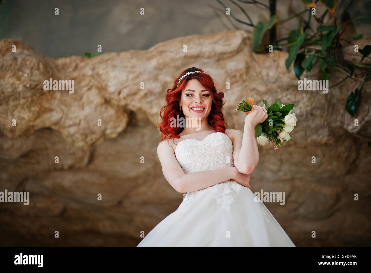 Rousse charmante épouse modèle avec bouquet de mariage à la main posée ...