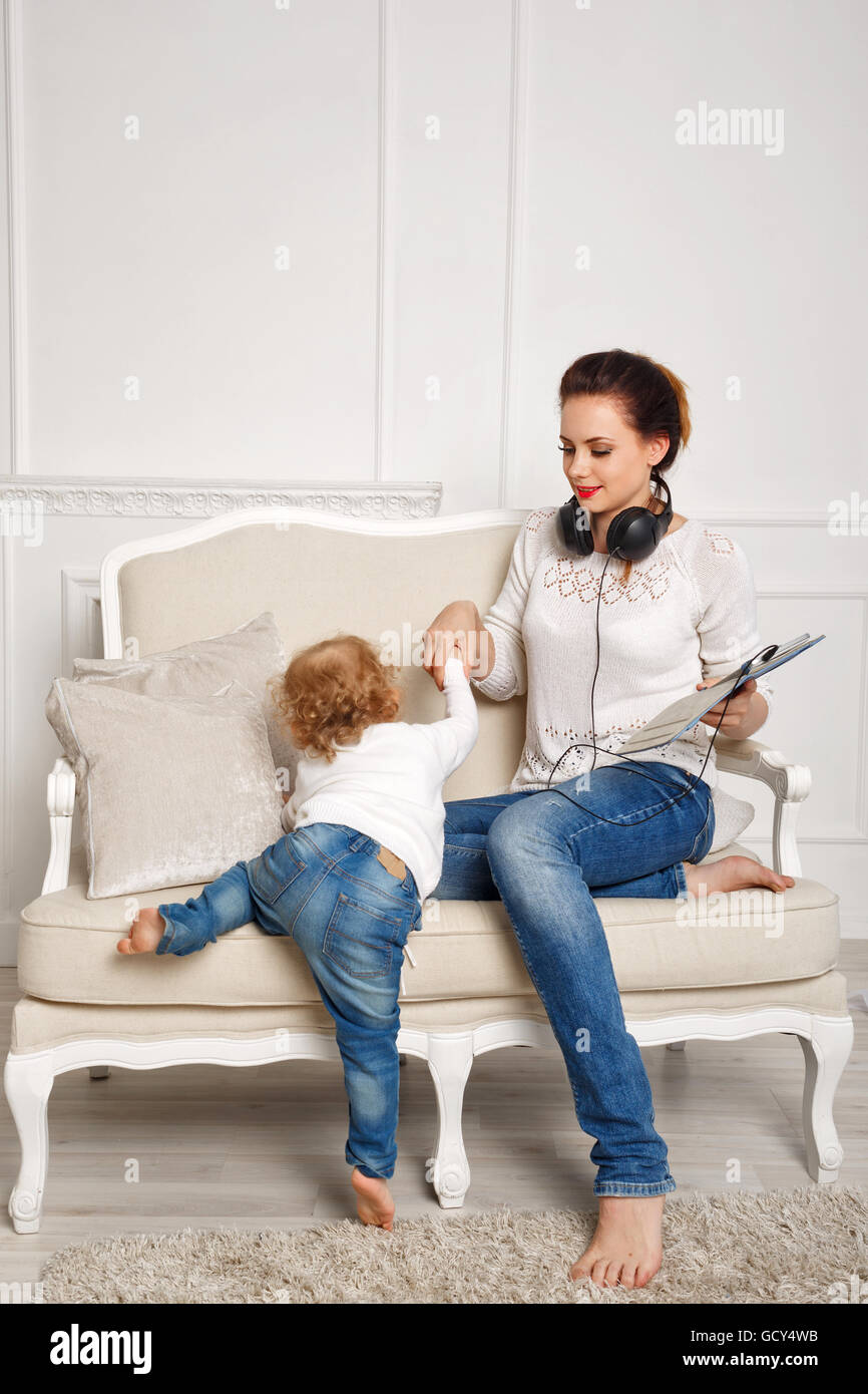Mère et fille à la maison. Bébé fille grimper sur la table, et sa mère ...