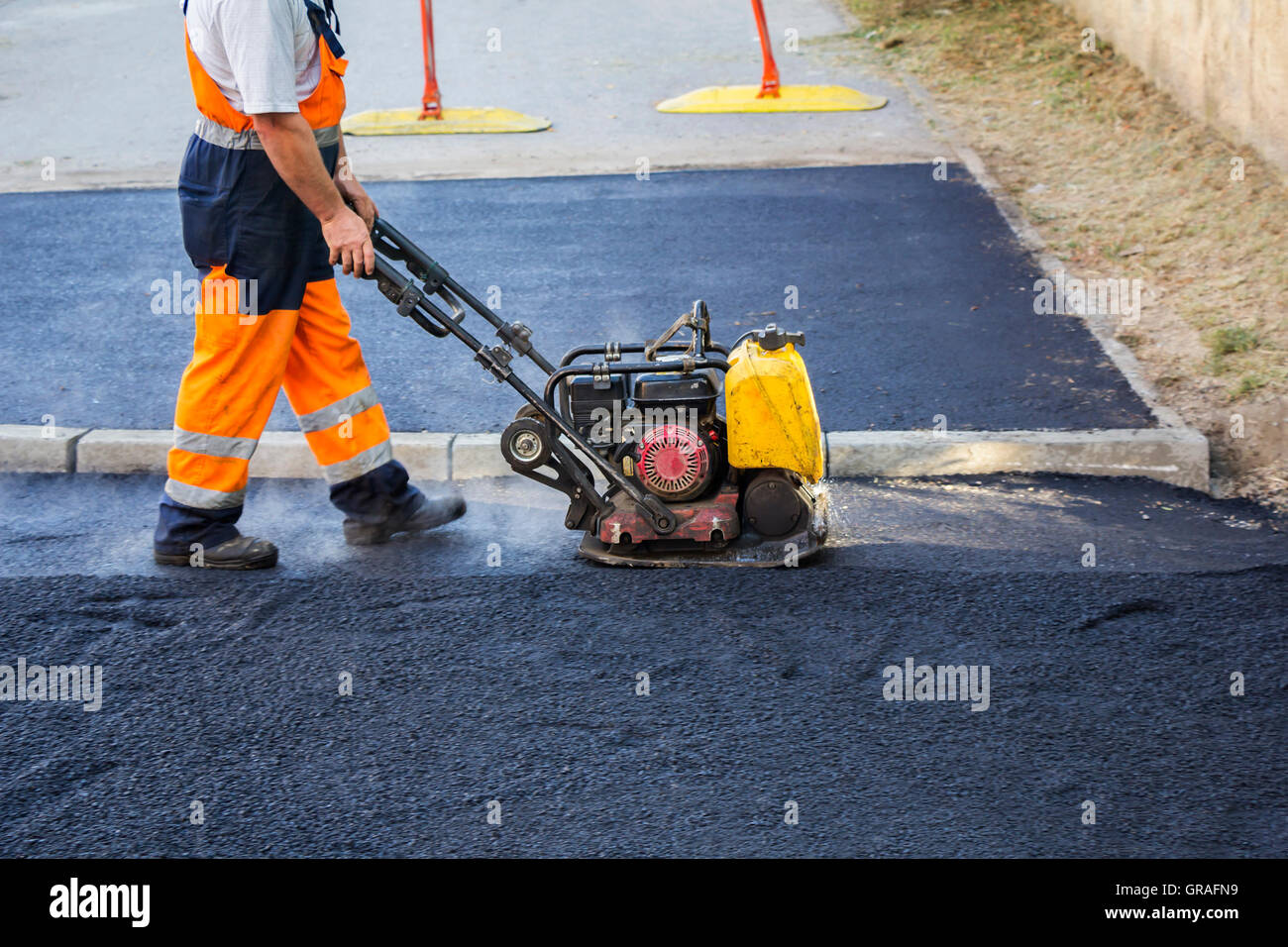 Travailleur utilise compacteur vibrant le compactage de l'asphalte à la ...