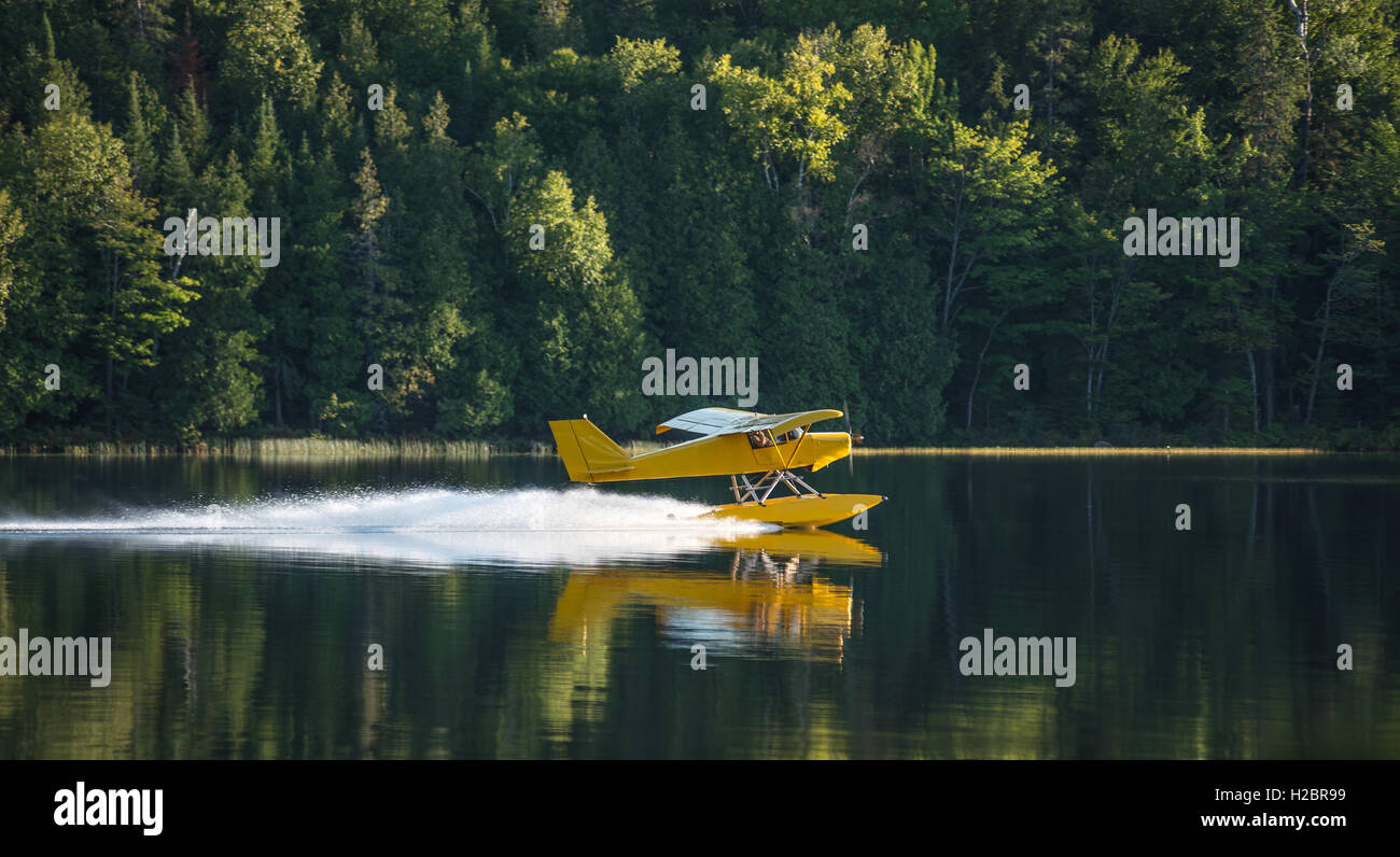 Petit avion jaune sur les pontons s'exécute à partir d'un lac de l'Est ...