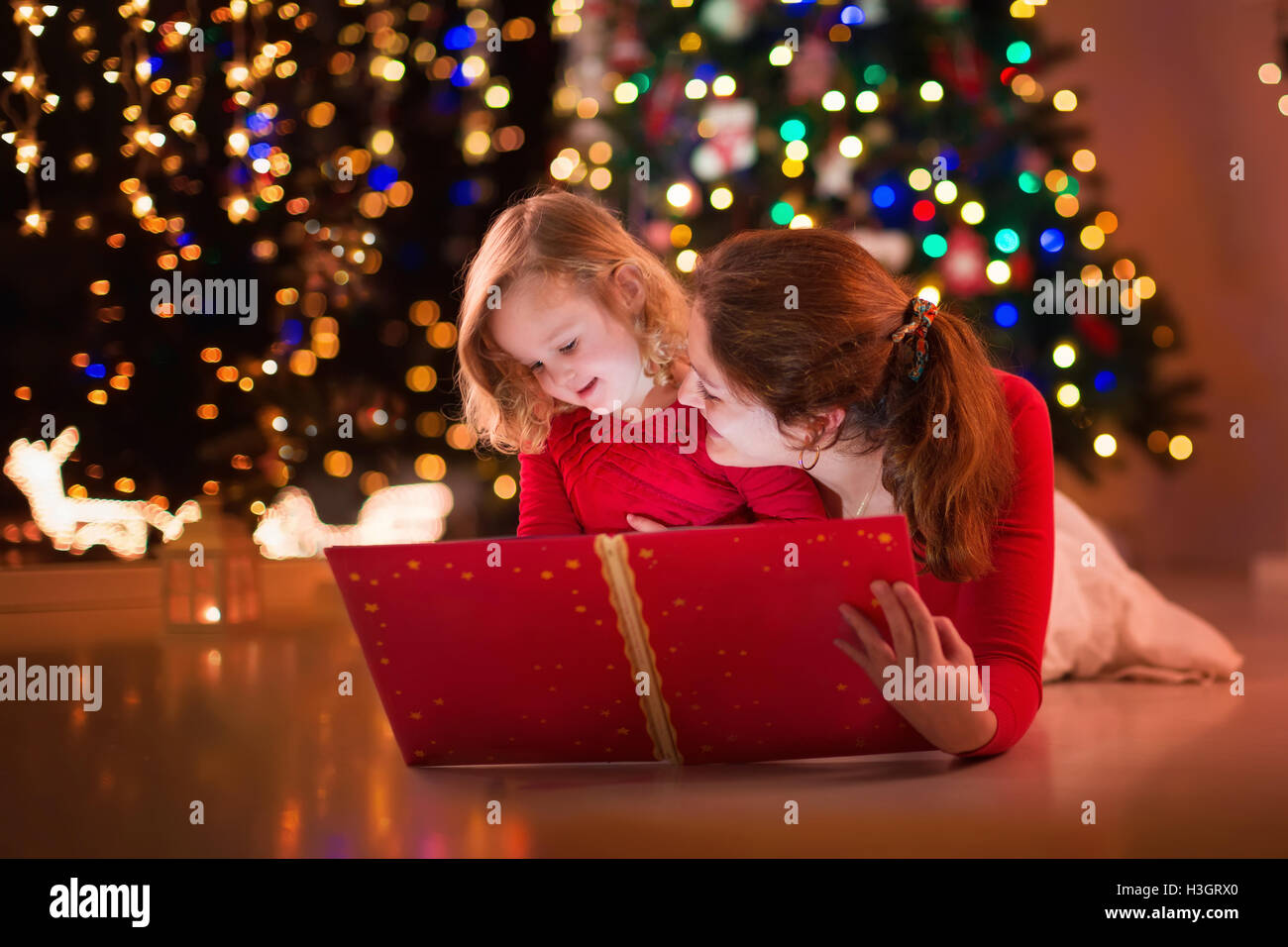 Mère et fille lire un livre à la cheminée la veille de Noël. Famille ...
