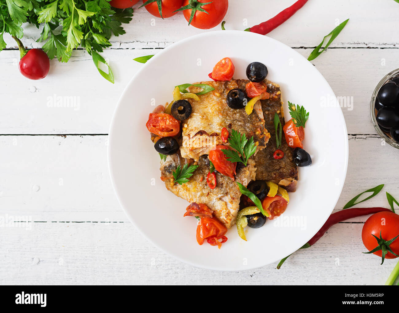 Filet de merlu frit avec de la tomate et les olives dans le style ...