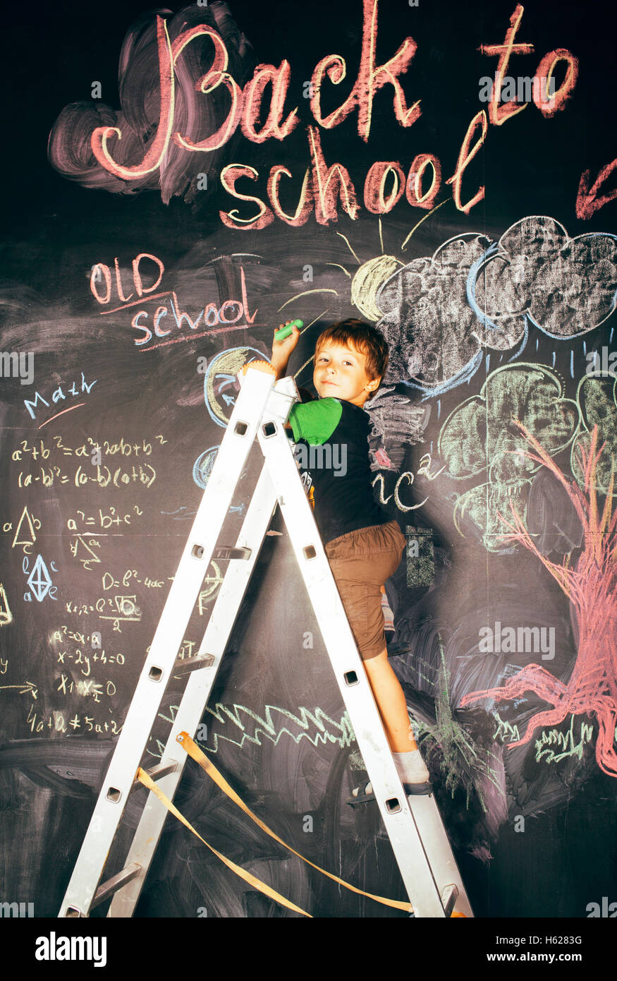 Peu mignon petit garçon au tableau noir en classe, de nouveau à l'école ...