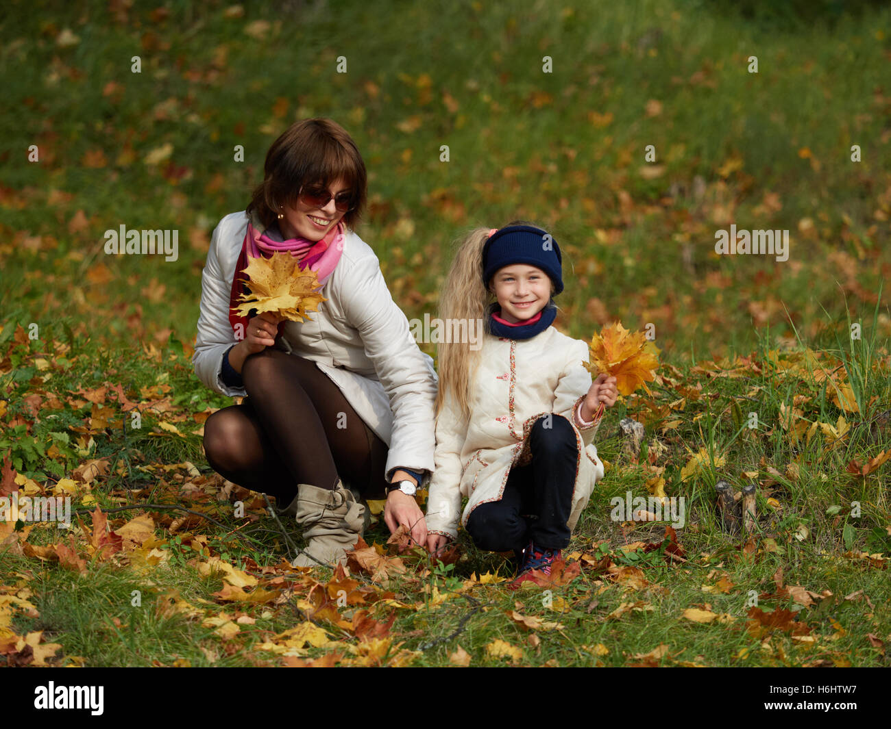 La mère et la fille sont à jouer avec les feuilles d'automne. Ils sont ...