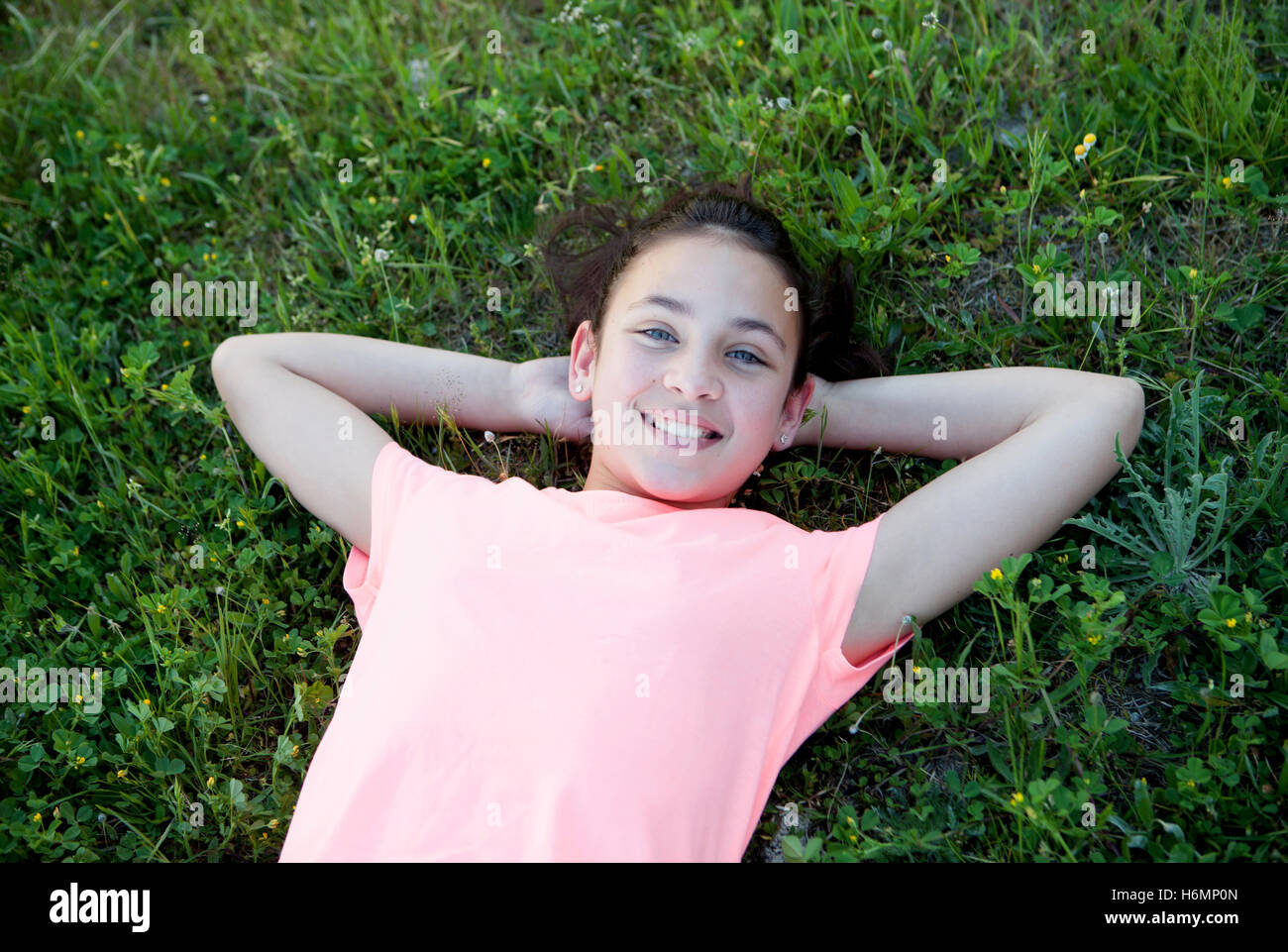 Belle preteen girl aux yeux bleus allongés sur l'herbe Photo Stock - Alamy