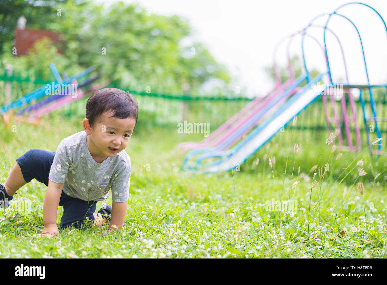 Peu d'Asian kid jouer et souriant à l'aire de jeux sous les rayons du ...