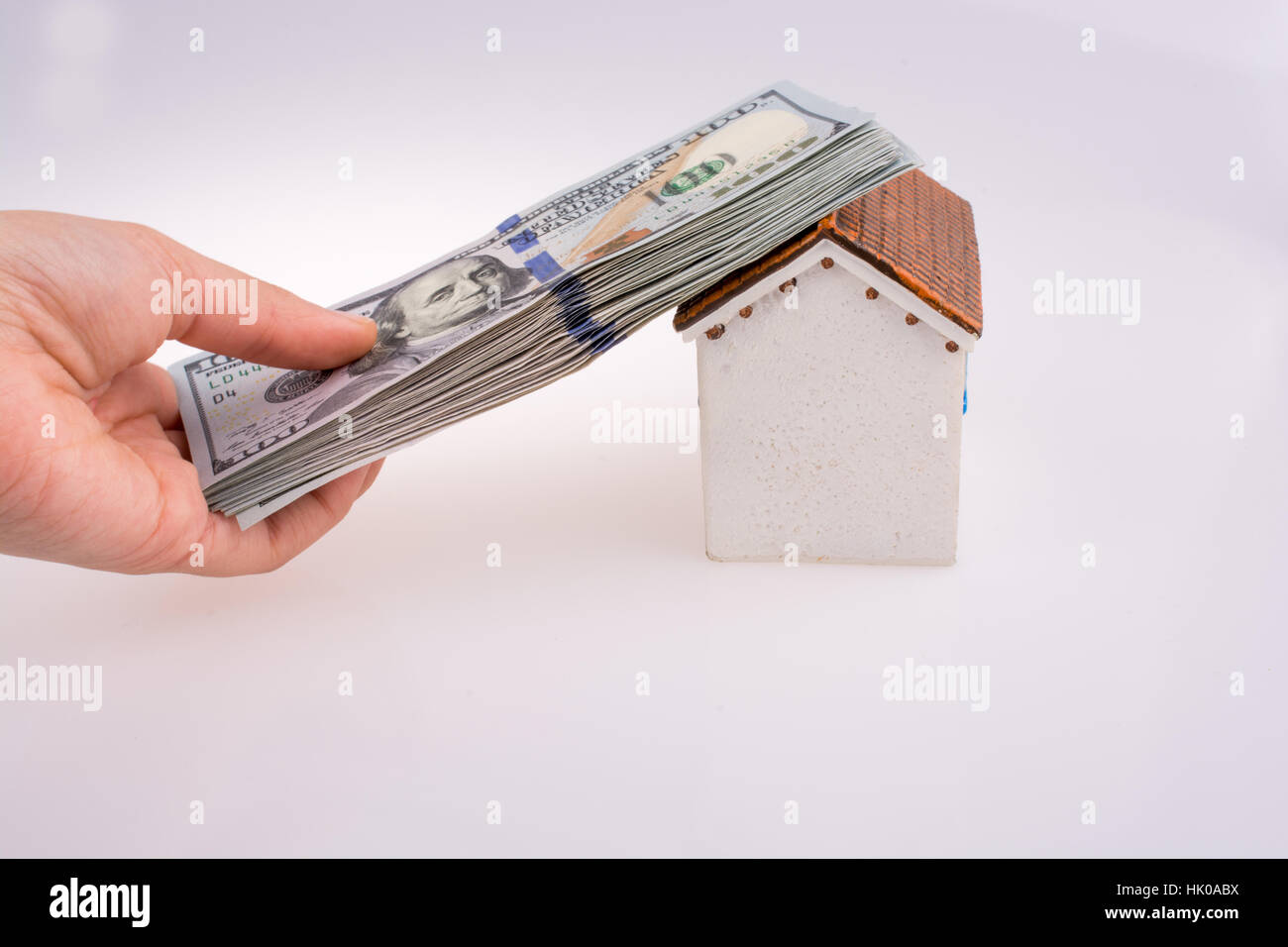 Hand holding American dollar billets sur le toit d'une maison modèle ...