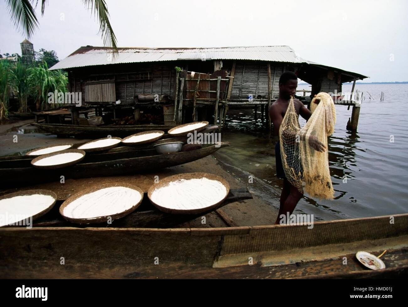 Un homme avec des filets en face de maisons construites sur l'eau, pile ...