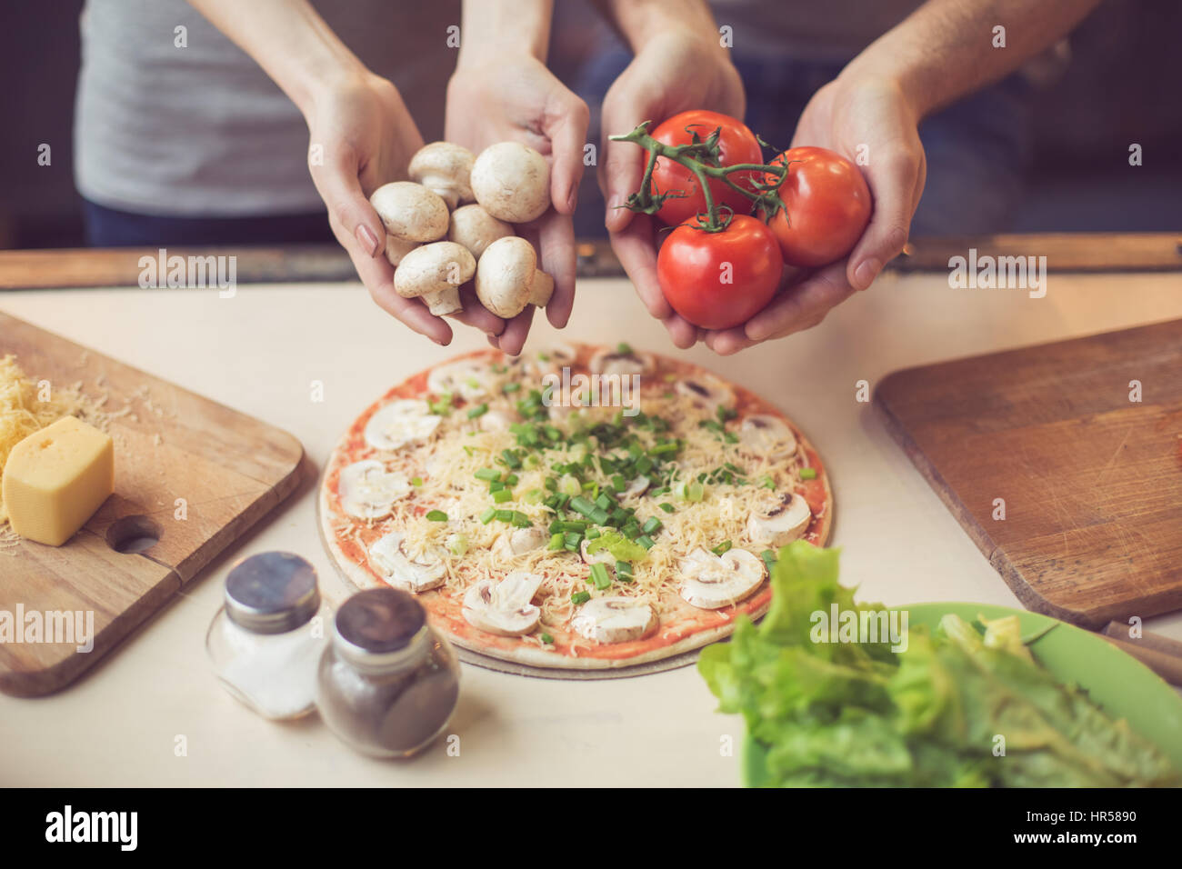 Pizza time. La photo en gros plan de mains tenant les champignons et ...