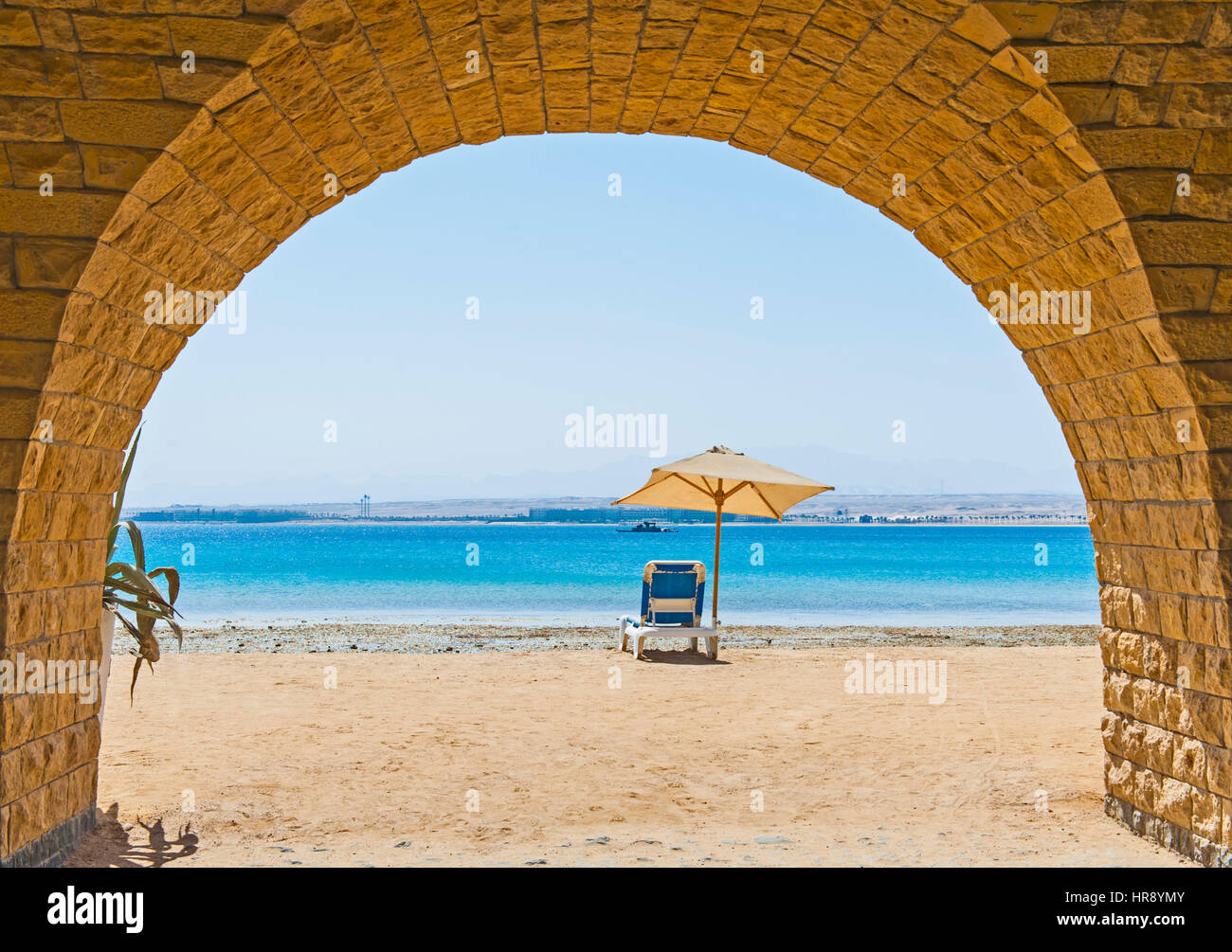 Vue sur une mer tropicale et plage avec transats grâce à une arche en ...