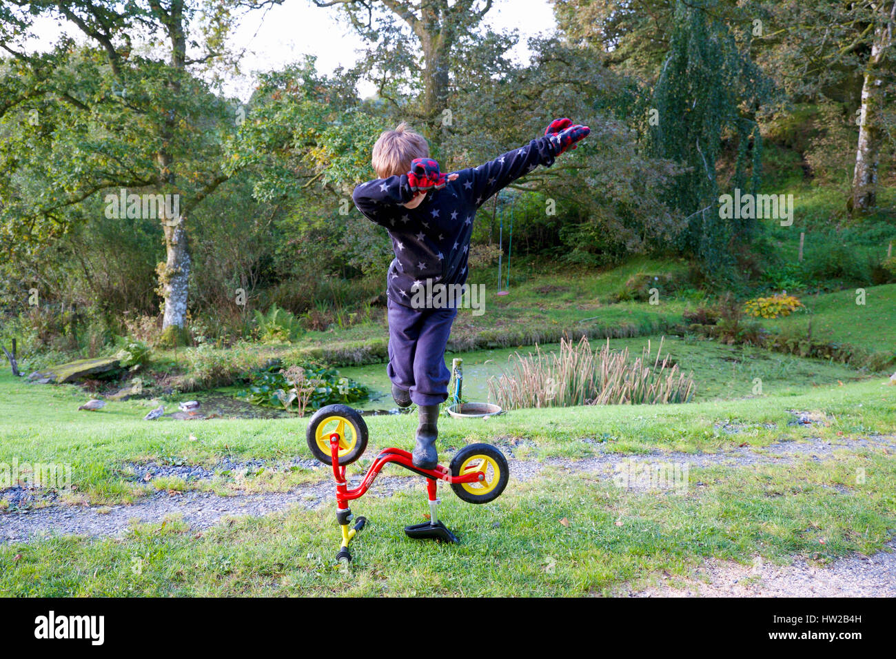 Garçon de 6 ans enfant enfant équilibre sur une jambe sur vélo retourné ...